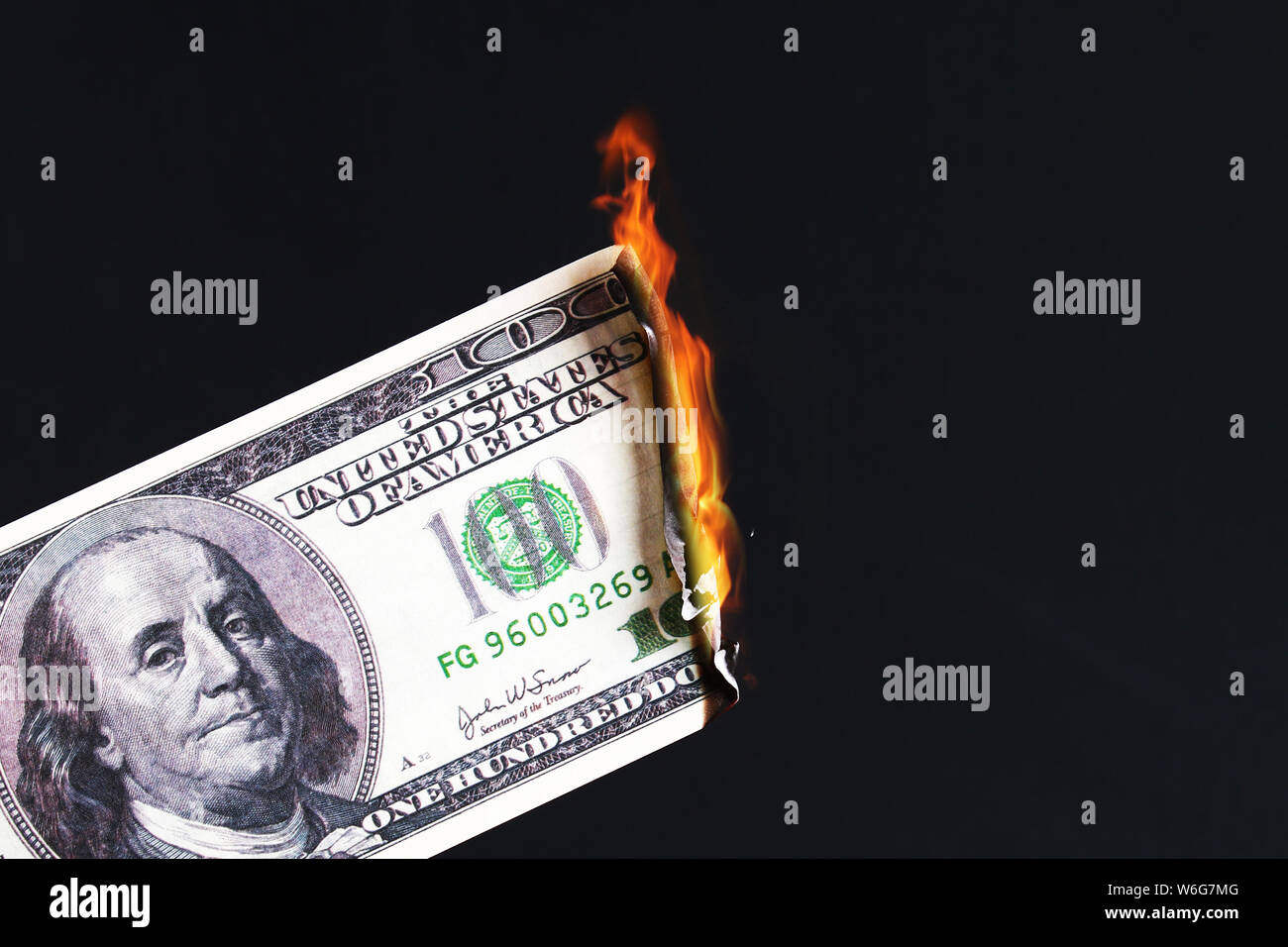 one hundred American dollar burning in fire flame on black paper ...