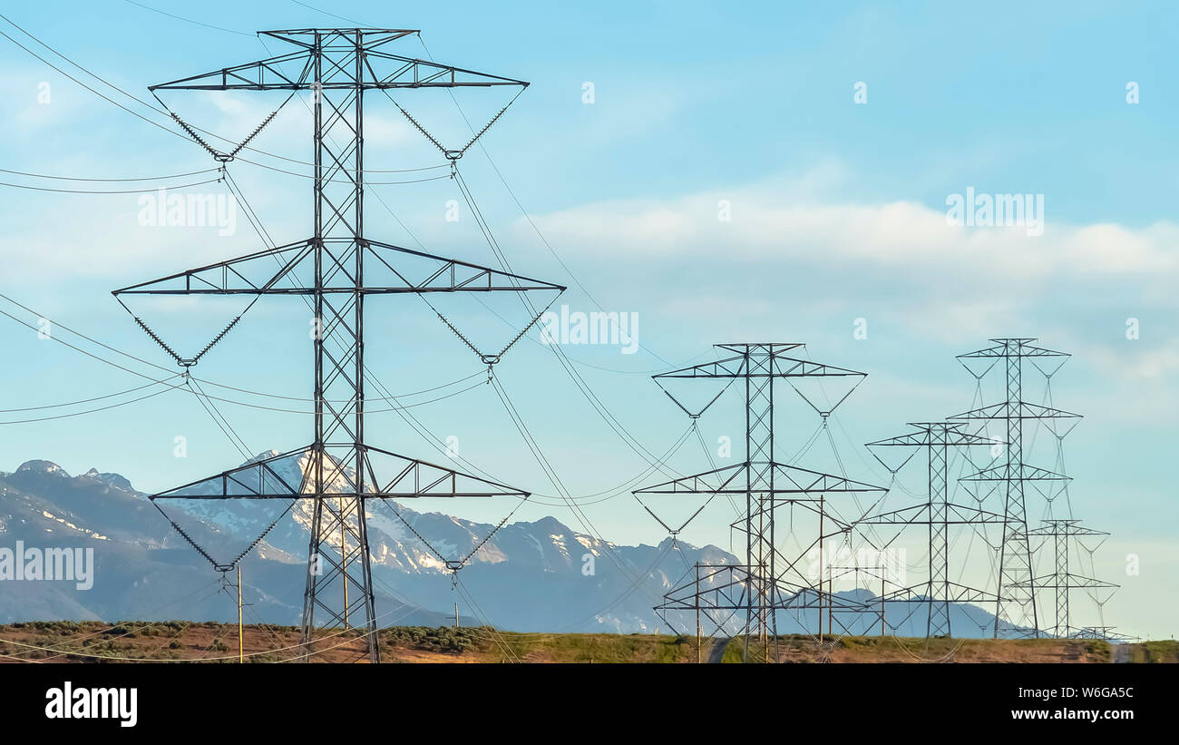Panorama Towering power lines in the valley against snow capped ...