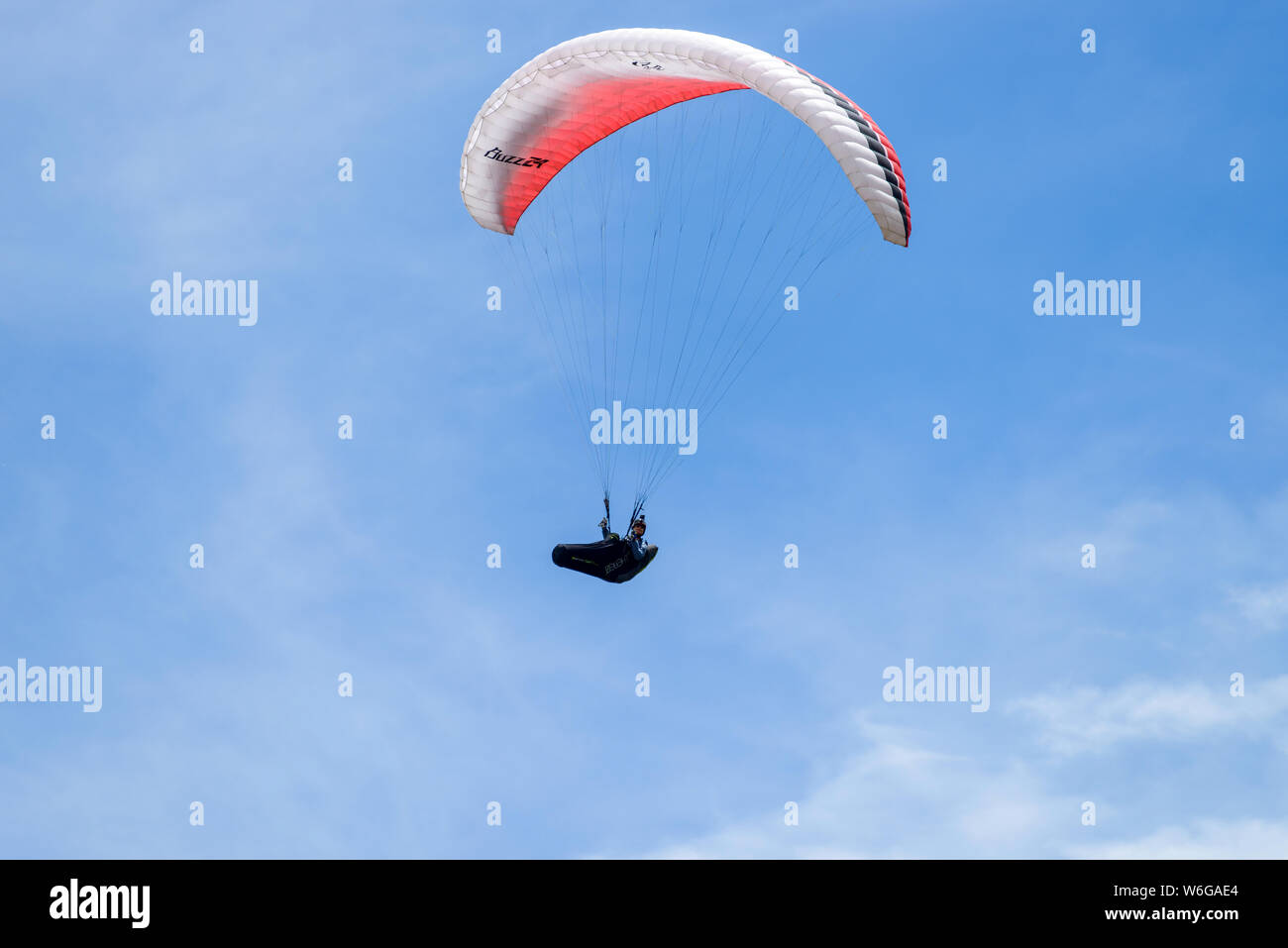 Paragliding - A colorful paraglider soaring high in blue sky above ...