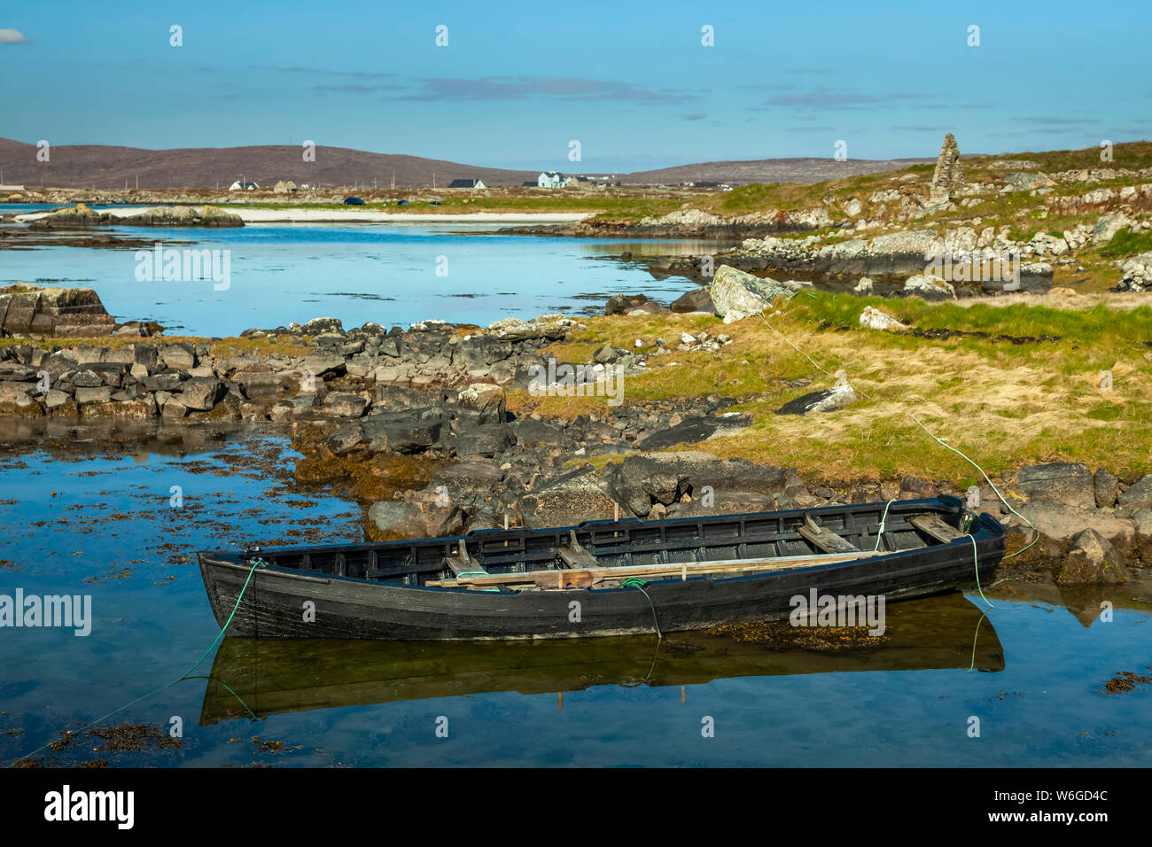 Small wooden rowboat moored along the shore of Galway Bay on Mweenish ...