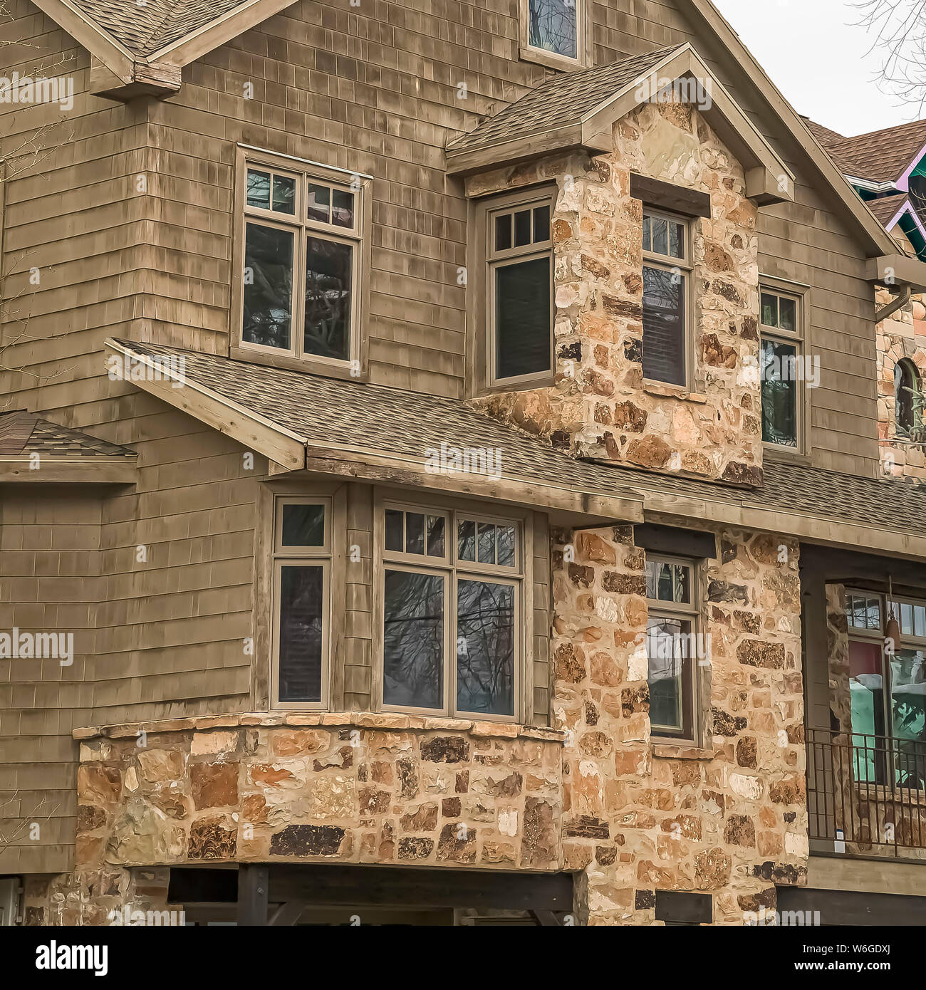 Square frame Home exterior with gray wall siding and stone wall accent ...