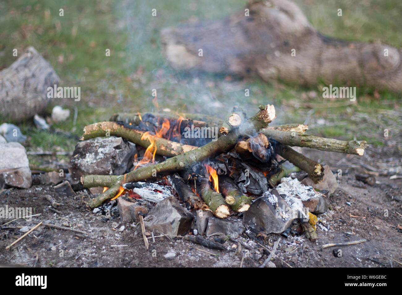 A small campfire made up of twigs and branches with rocks surrounding ...