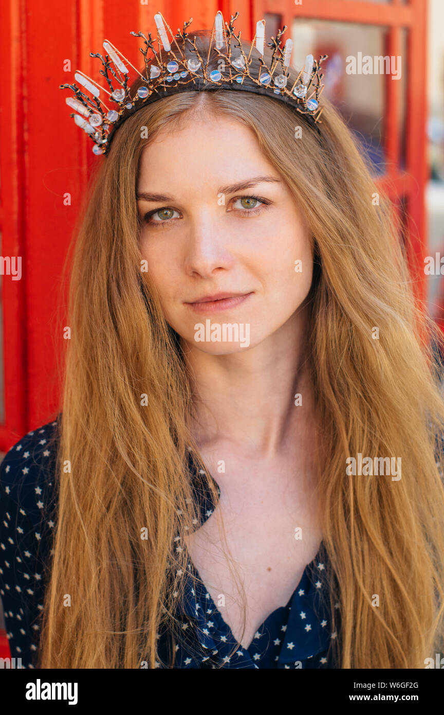 Young woman with crown on head near red telephone cabin Stock Photo - Alamy