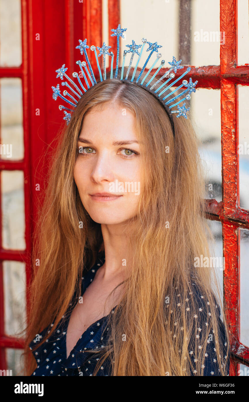 Young woman with crown on head in red telephone cabin Stock Photo - Alamy