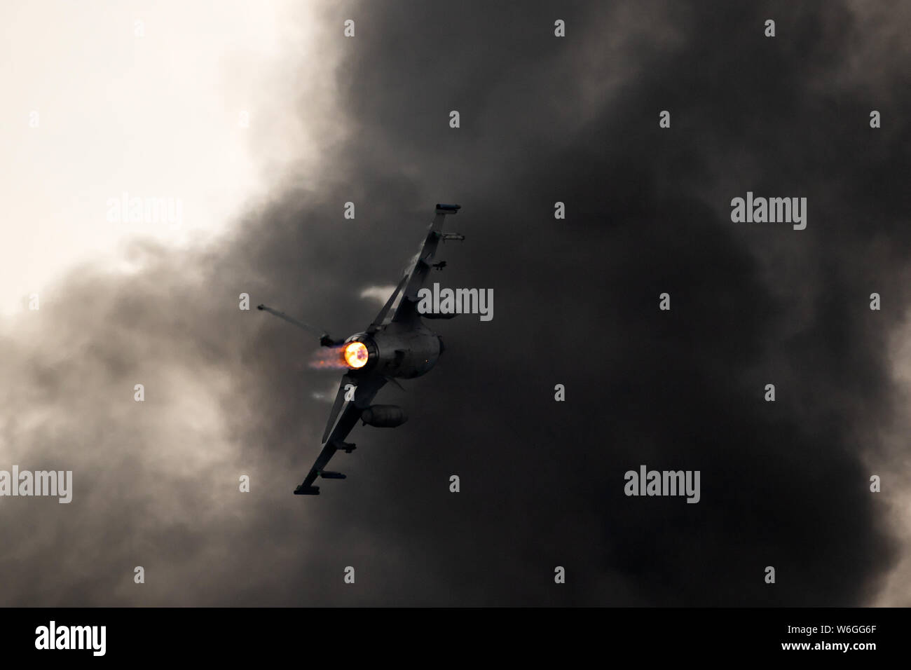 Fighter jet flying with afterburner through a cloud of smoke after an ...