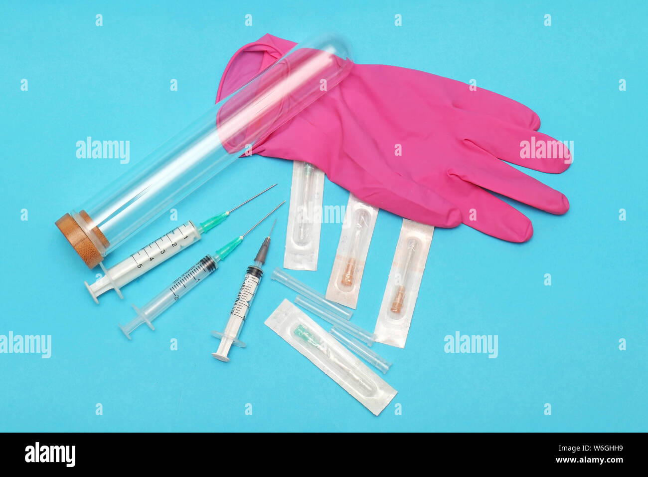 Pink surgical latex glove with glass test tube and syringes and needles ...