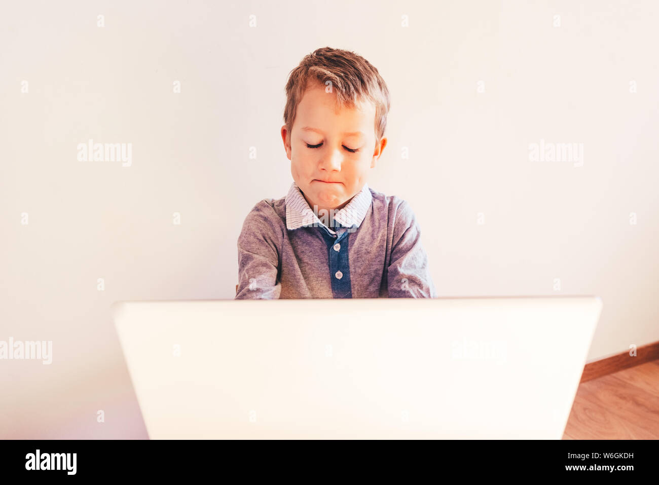 Child with very expressive face in front of a laptop with angry gesture ...