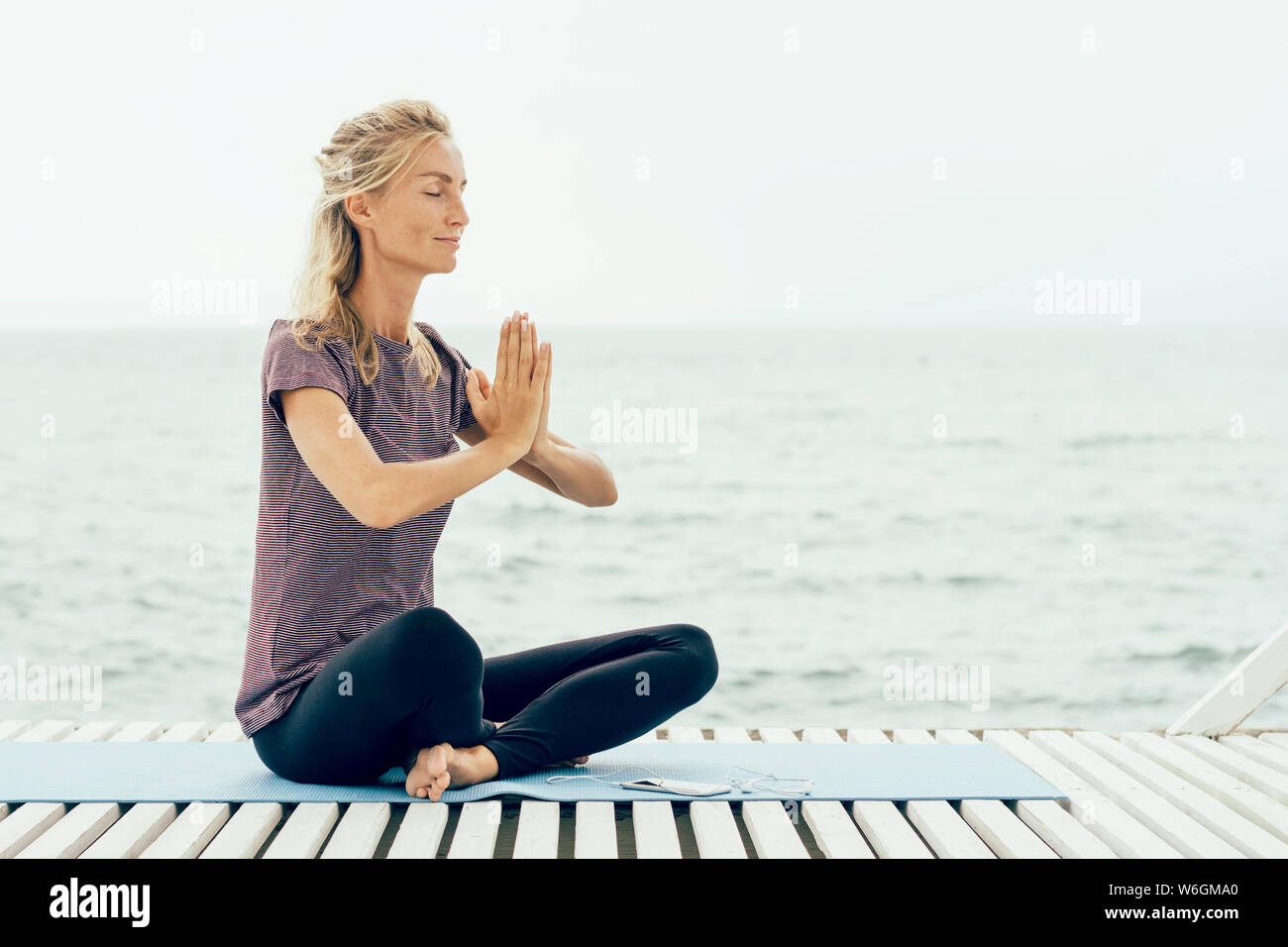 Young woman in namaste greeting pose by the sea Stock Photo - Alamy