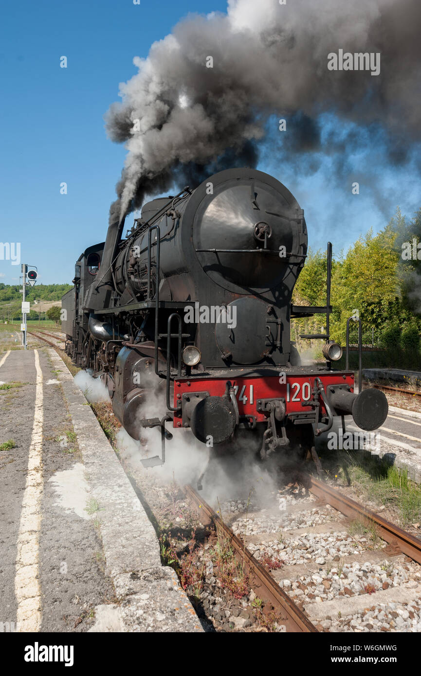 Steam locomotive stops on the tracks, snorting smoke and hot steam ...