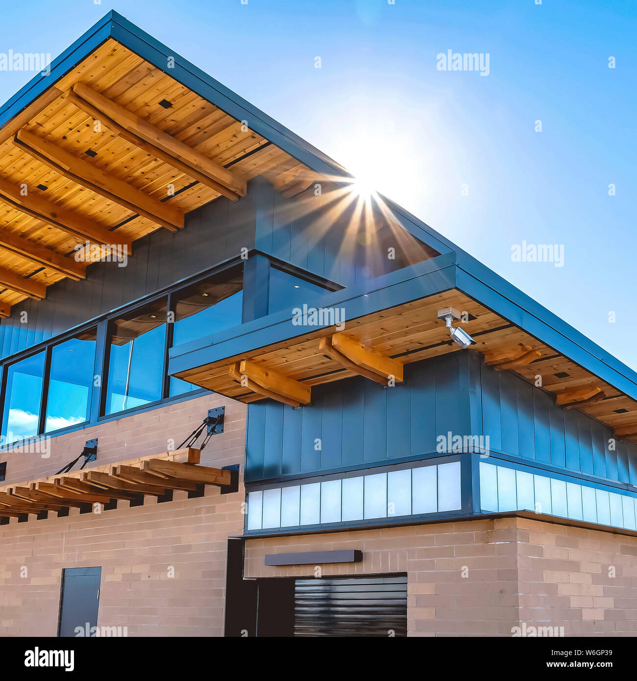 frame Blue sky and bright sun over a park building with flat roof and ...