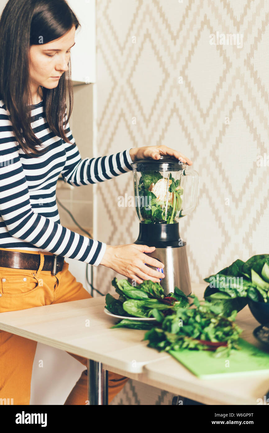 A girl in her kitchen grinds smoothie ingredients in a blender Stock ...