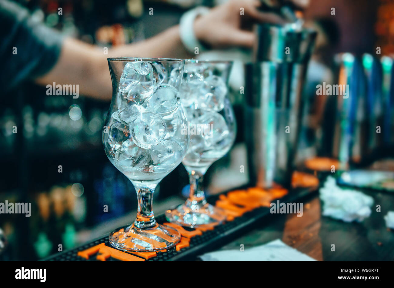 Two glasses with ice. Professional bartender pours alcoholic drink into glasses on bar Stock ...