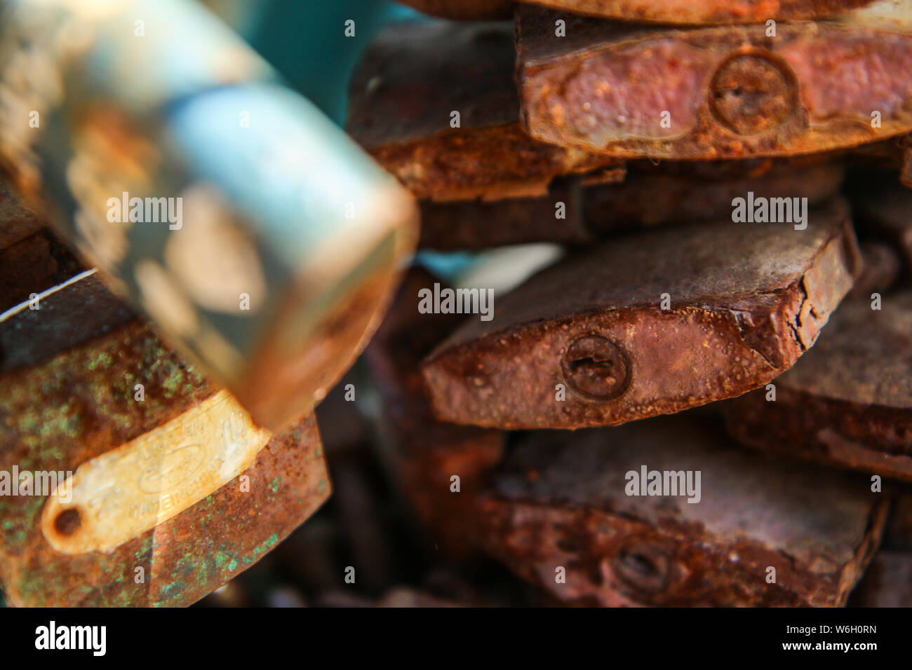 A detail of several old and rusty locks hanging on a handrail on a ...
