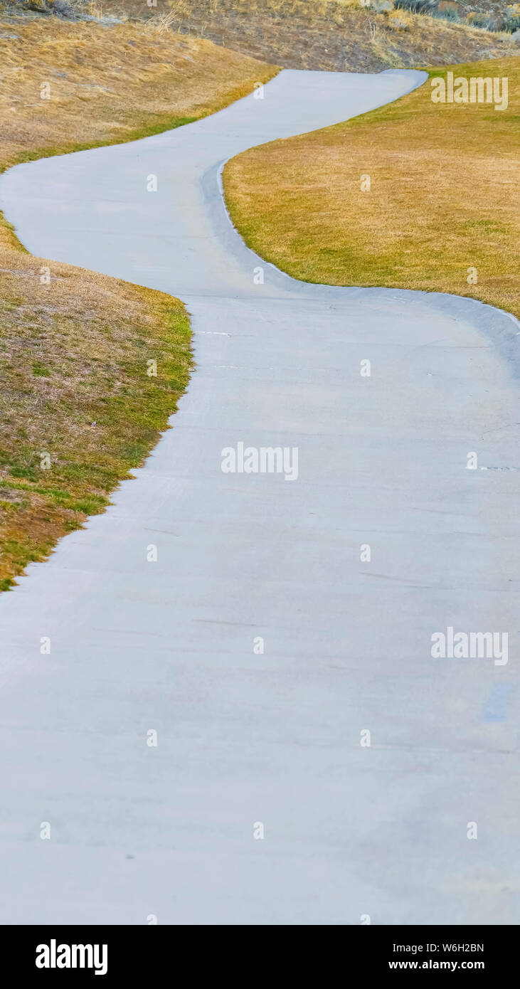Vertical frame Close up of a narrow pathway paved with concrete viewed ...