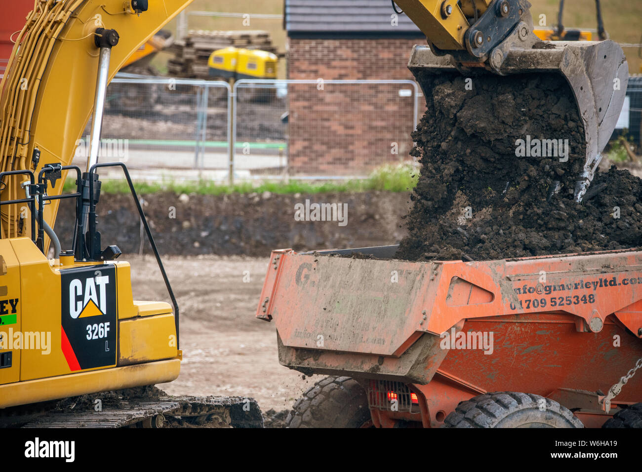 A digger and dump truck move dirt to make room for the foundations ...