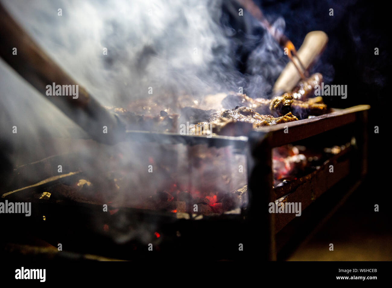 flaming heavy smoking charcoal grill with open fire, meat already on ...