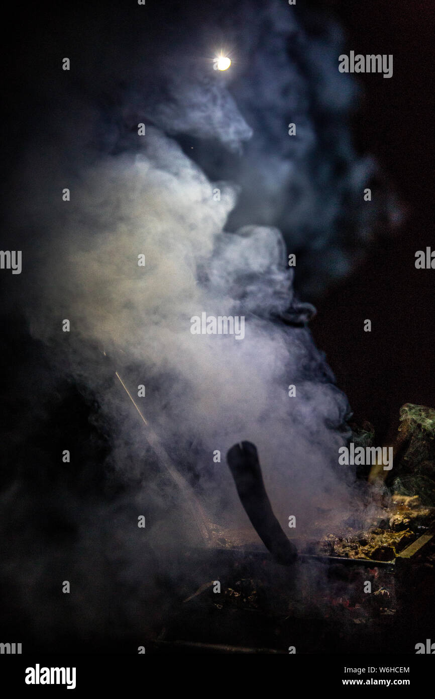 flaming heavy smoking charcoal grill with open fire, meat already on ...