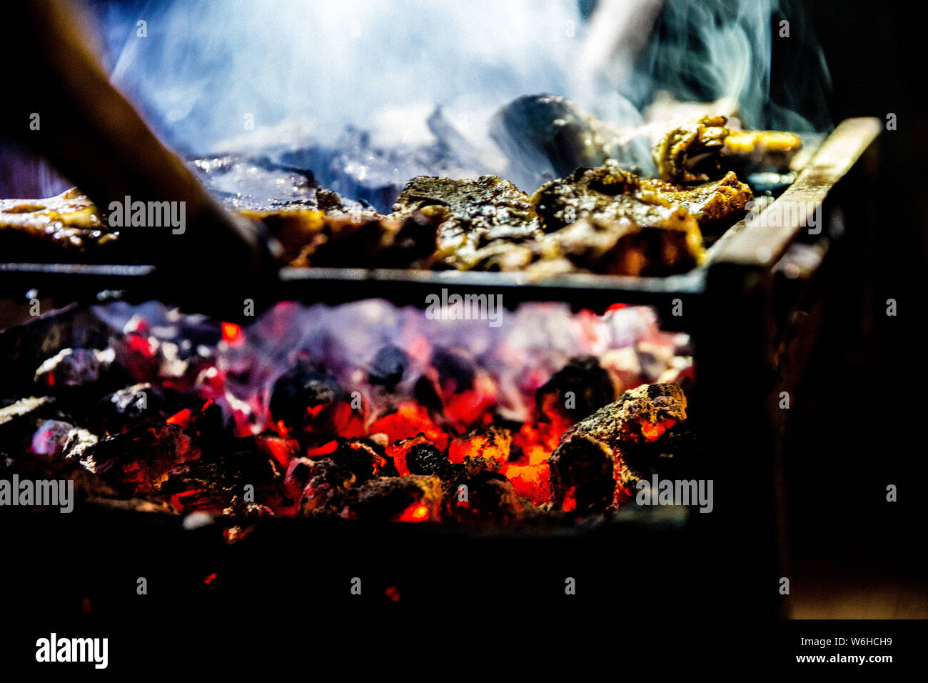 flaming heavy smoking charcoal grill with open fire, meat already on ...