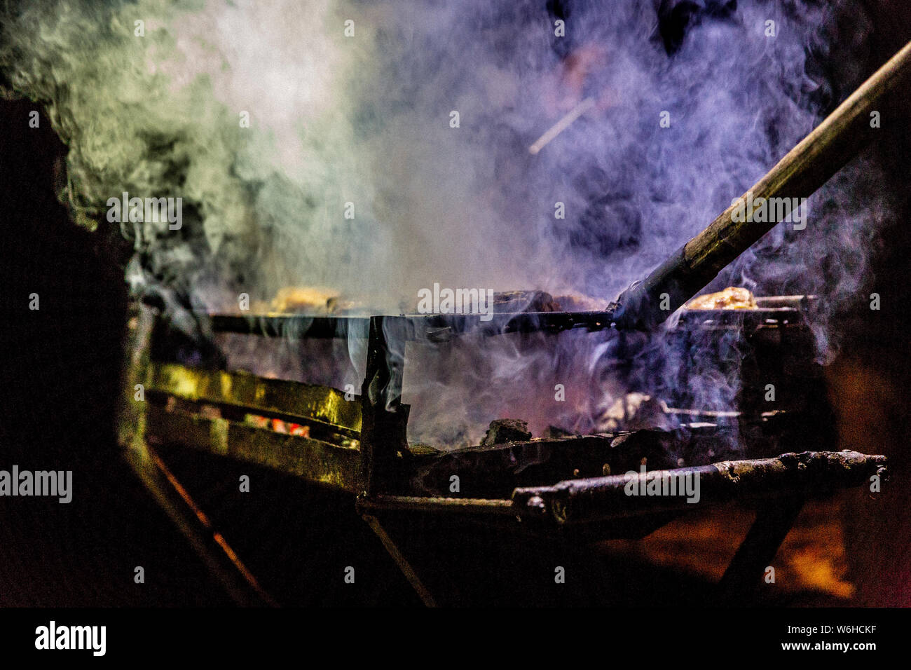 flaming heavy smoking charcoal grill with open fire, meat already on ...