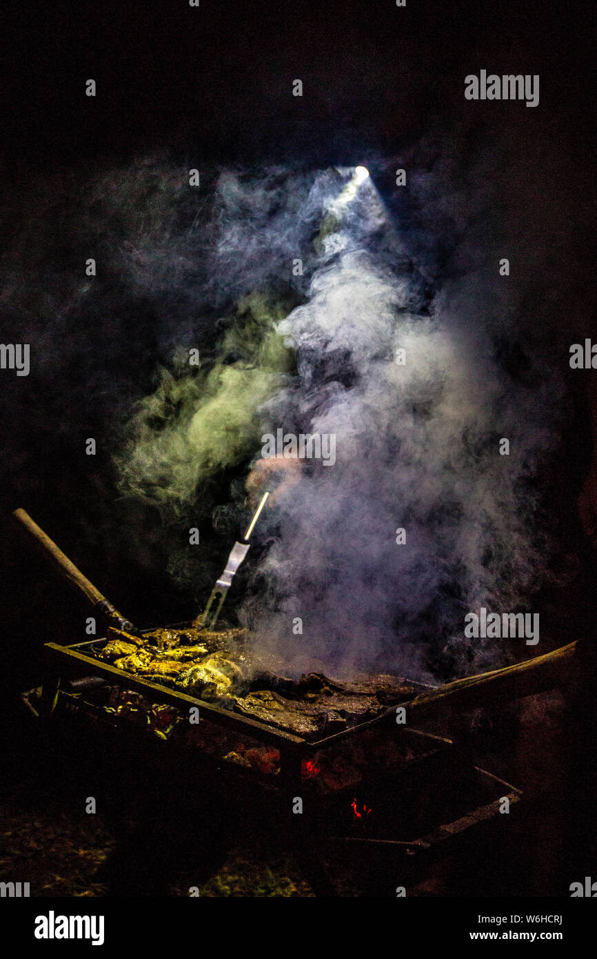 flaming heavy smoking charcoal grill with open fire, meat already on ...