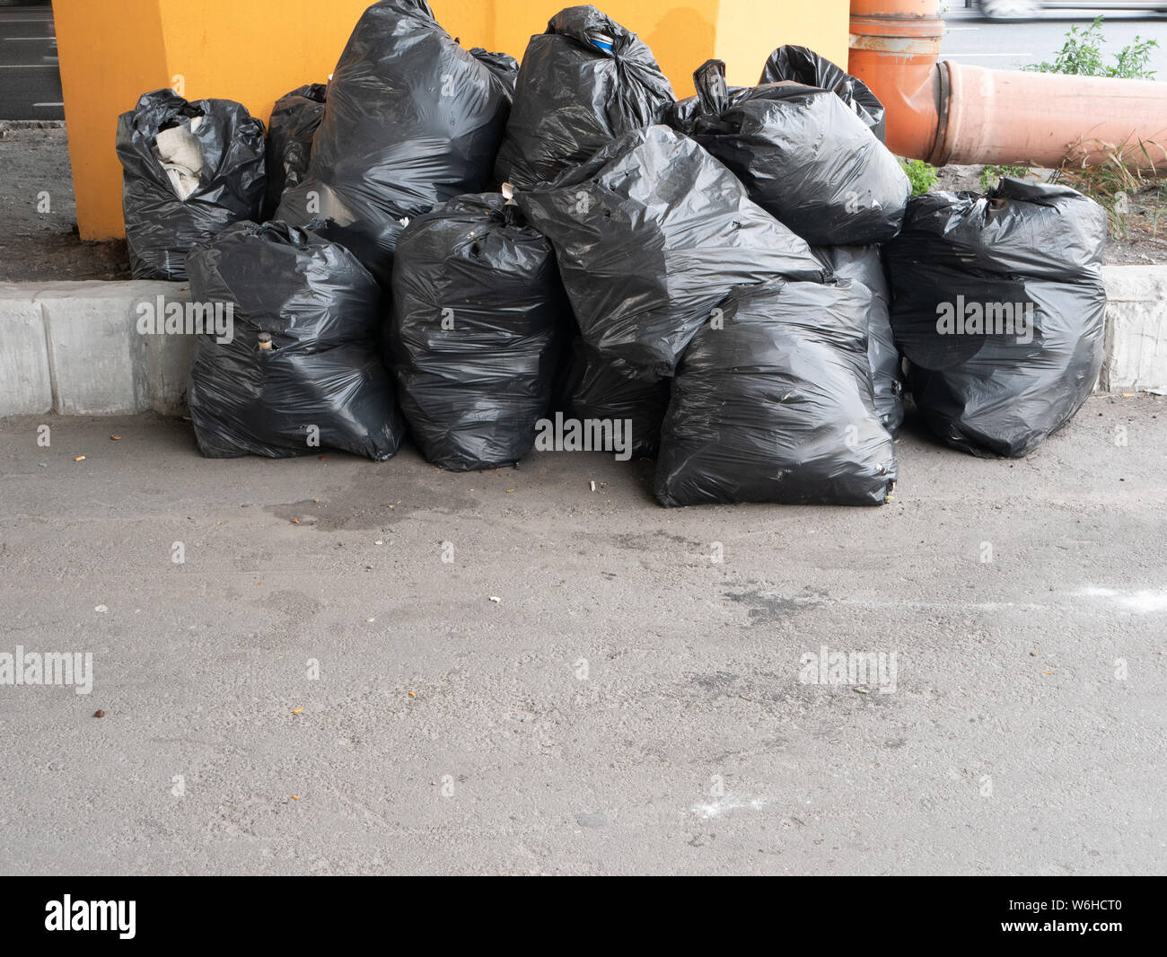 big pile of black plastic garbage trash bags. stacked on the street ...