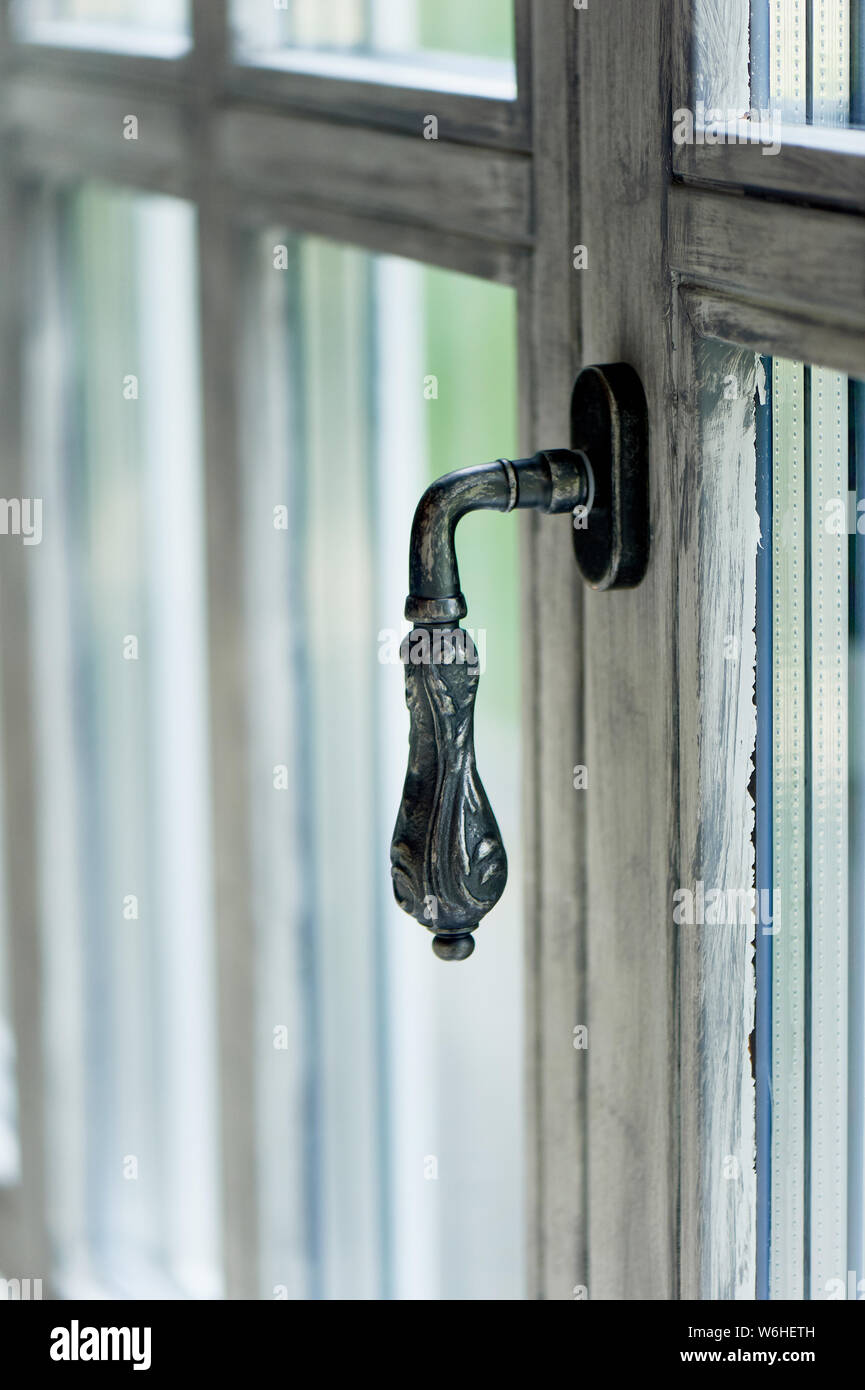 Forged handle on a light-colored wooden window.Classical interior Stock ...