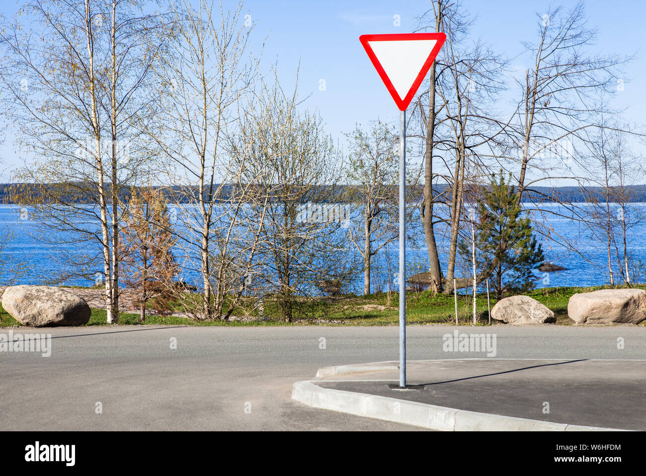 Road sign - give way, on a background of blue lake Stock Photo - Alamy
