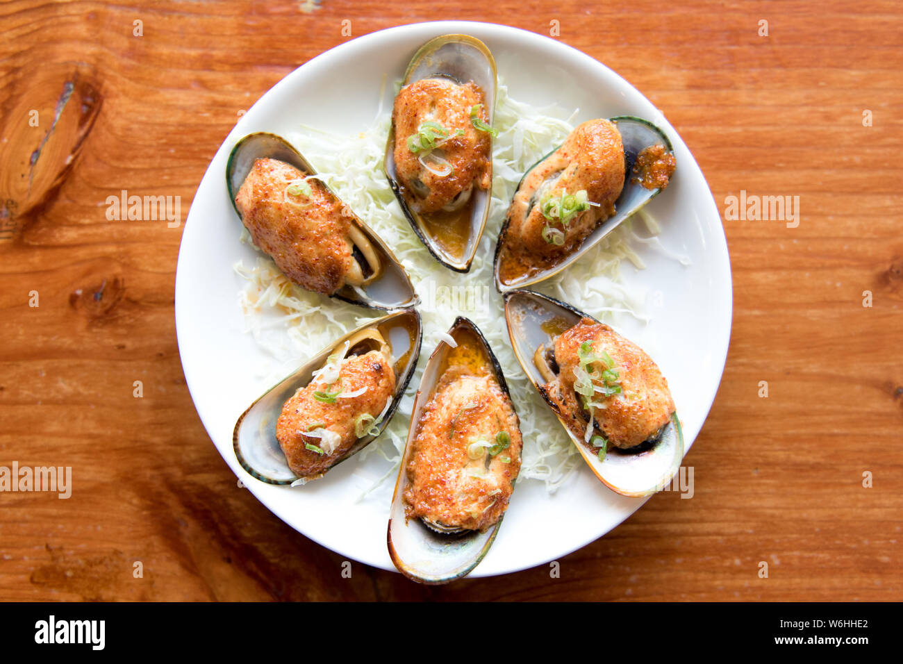 baked muscles sit on a white plate on a wood table. seafood Stock Photo ...
