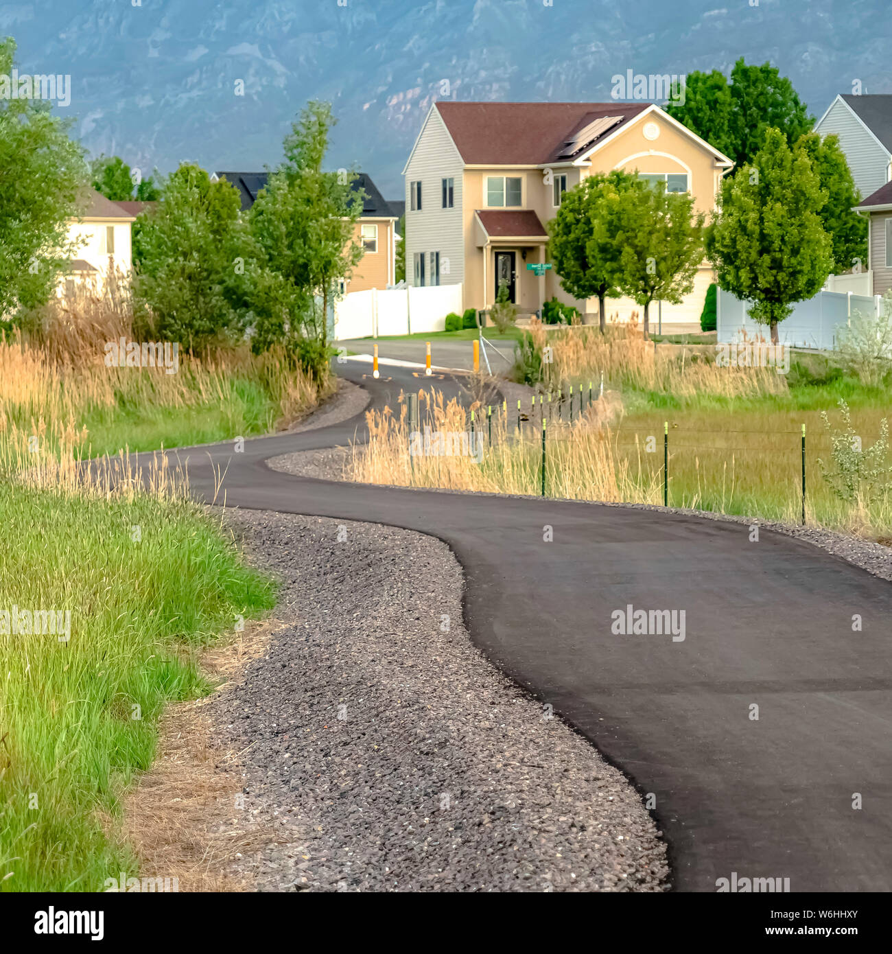 Square Road winding amid grassy terrain with homes trees and mountain ...