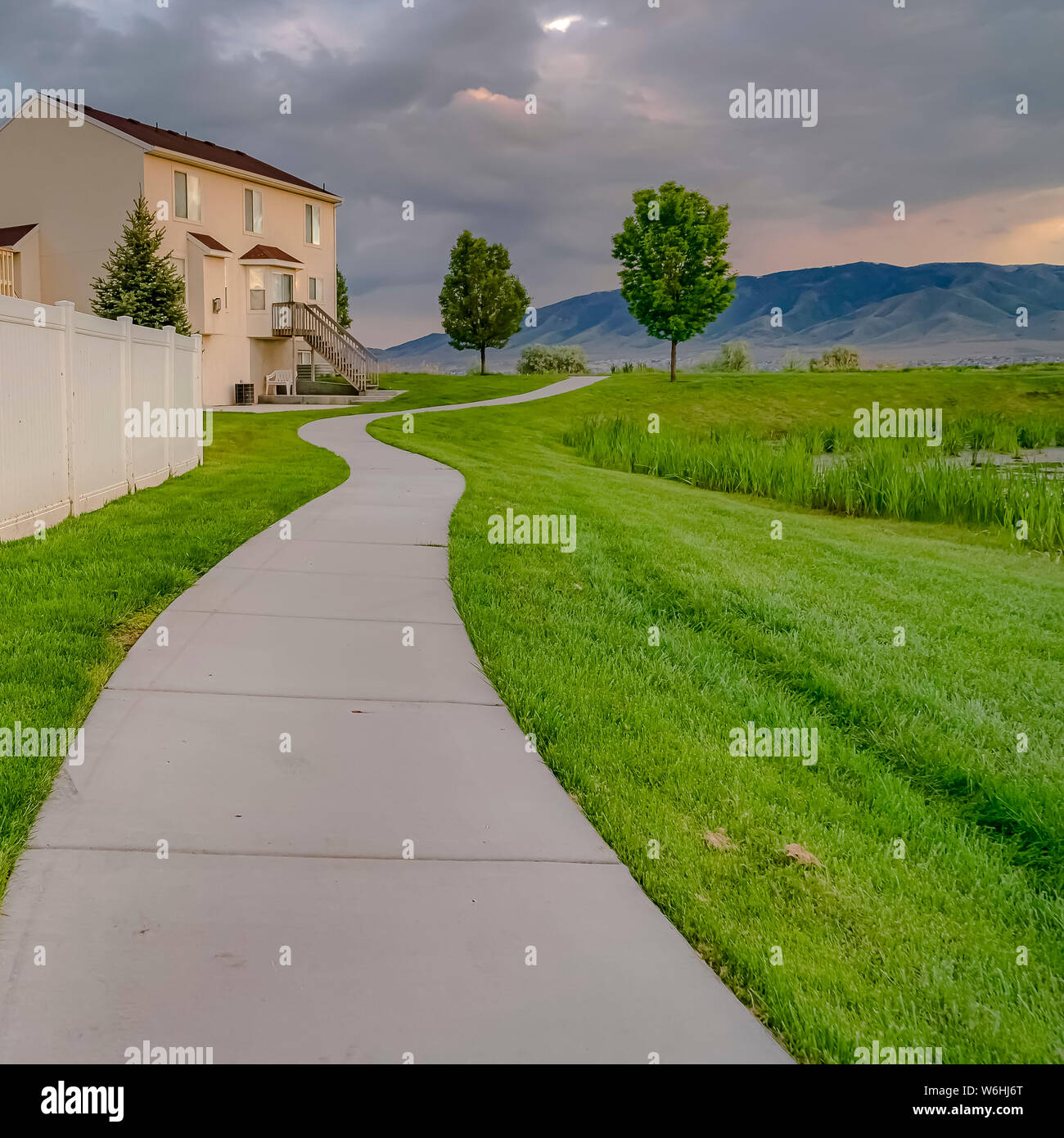 Square Paved walkway in front of homes with view of a pond and vast ...