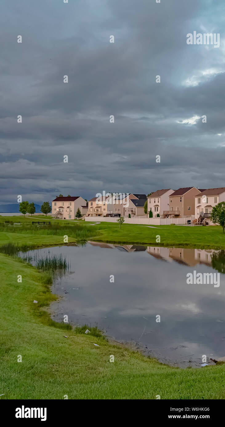 Vertical Scenic neighborhood park with a shiny pond and pathway under ...