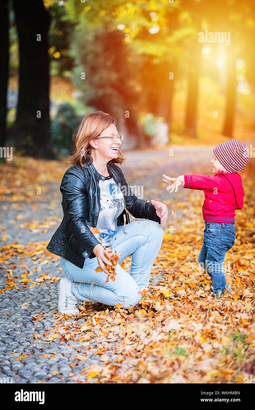 Happy little child, baby boy laughing and playing in the autumn park ...