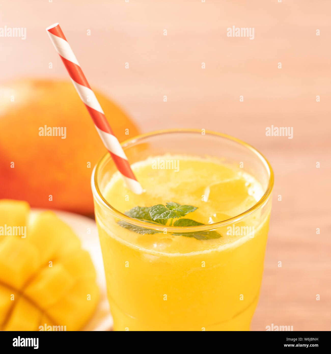 Fresh mango juice with beautiful chopped pulp flesh and straw on bright ...