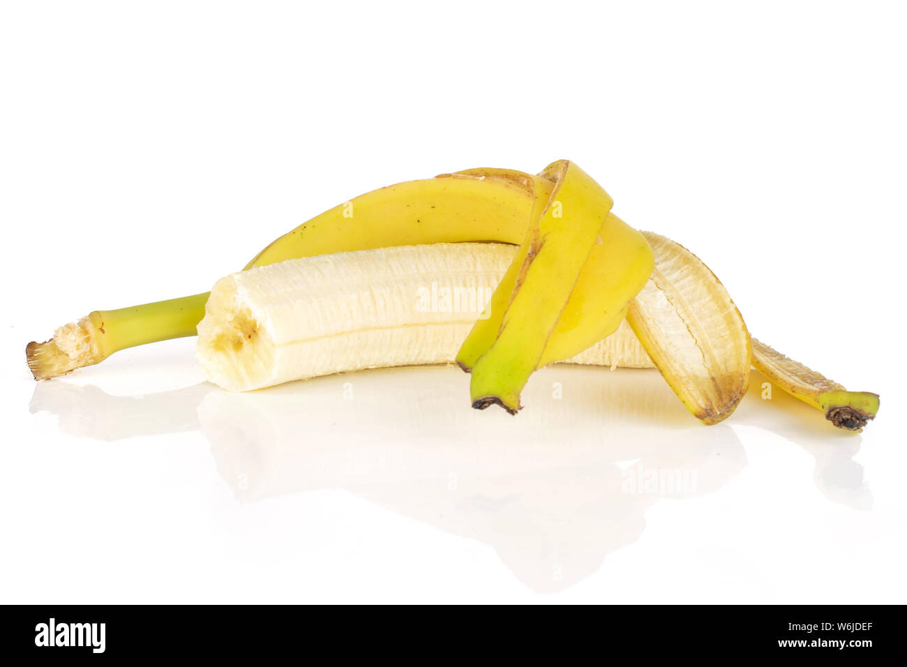 One whole ripe yellow banana bitten off with its skin on the top ...