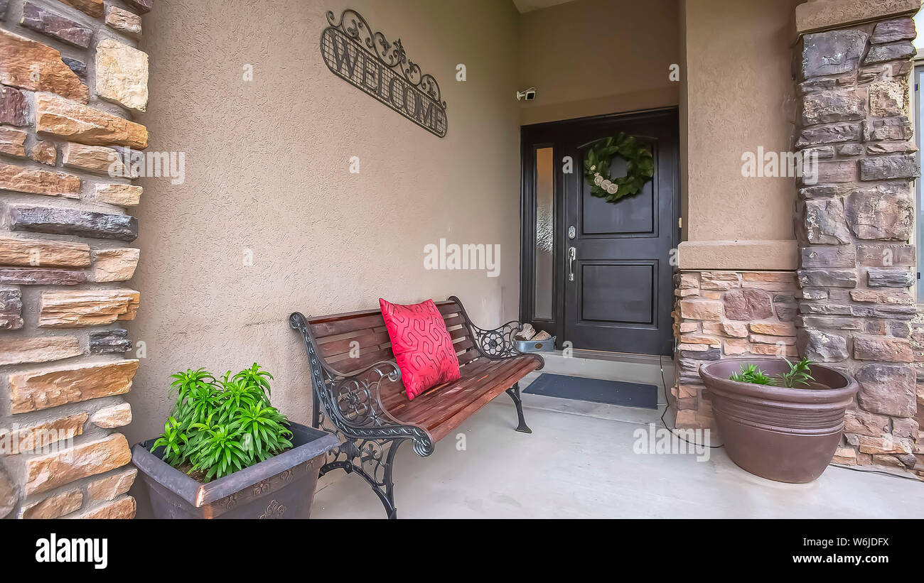 Panorama Home facade with bench welcome sign and potted plants on the ...