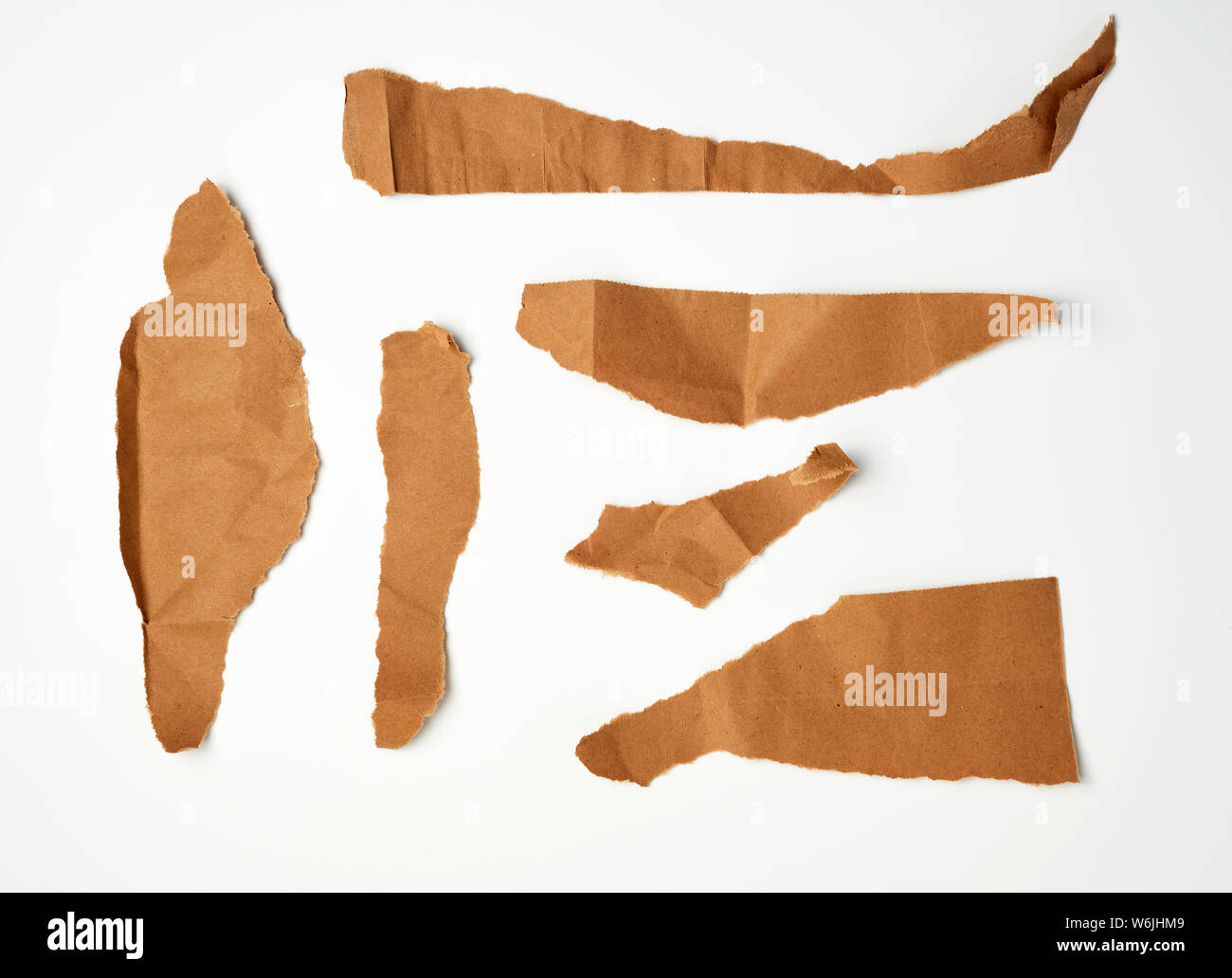 torn brown pieces of parchment paper on a white background, flat lay ...