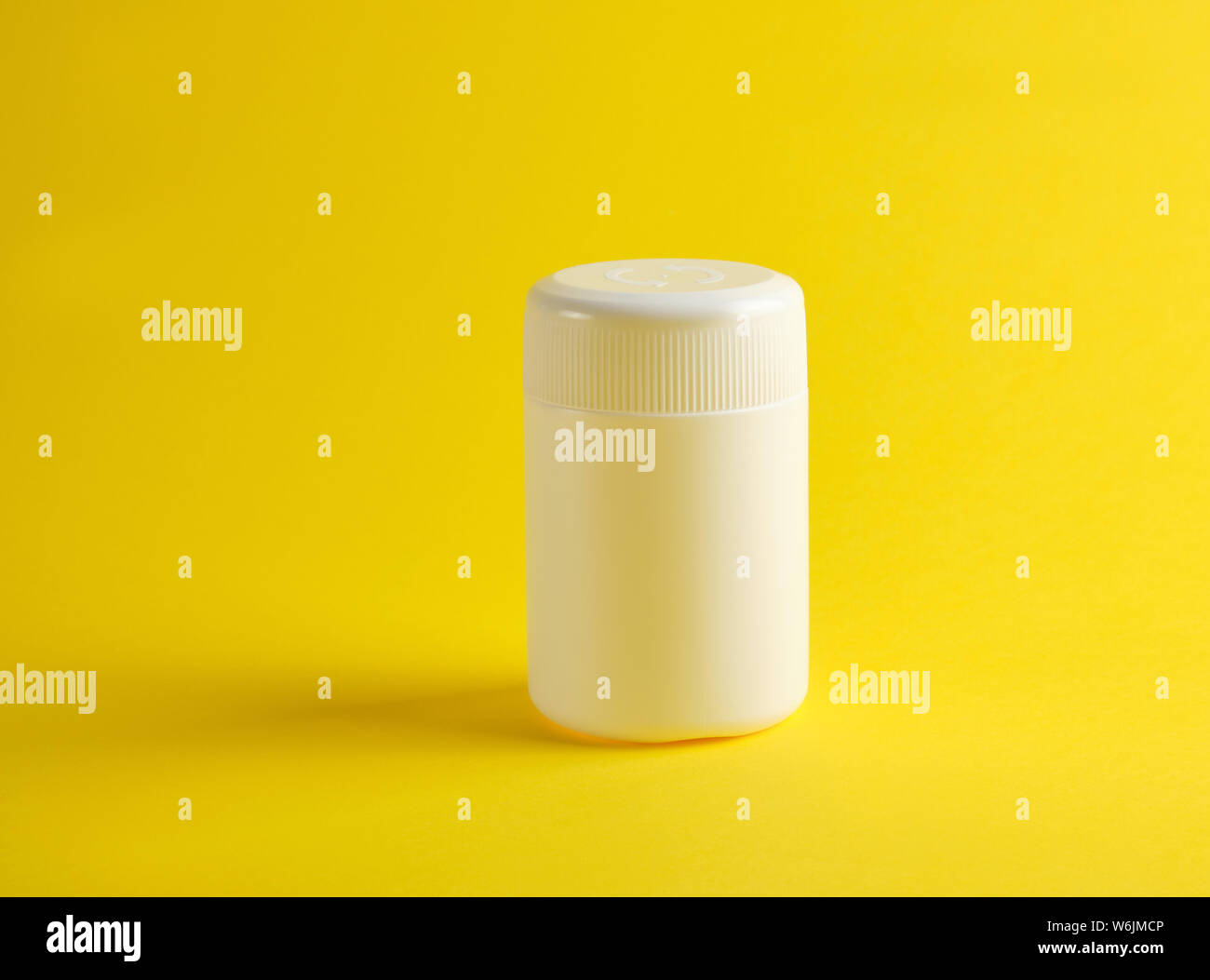 closed white plastic jar for medicines on a yellow background, copy ...