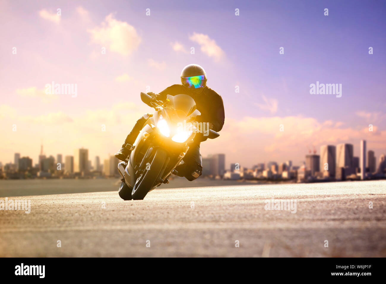 man riding sport motorcycle lean on curve road against urban skyline ...