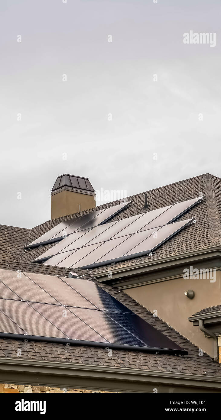 Vertical Solar panels mounted on the dark pitched roof of a home under ...