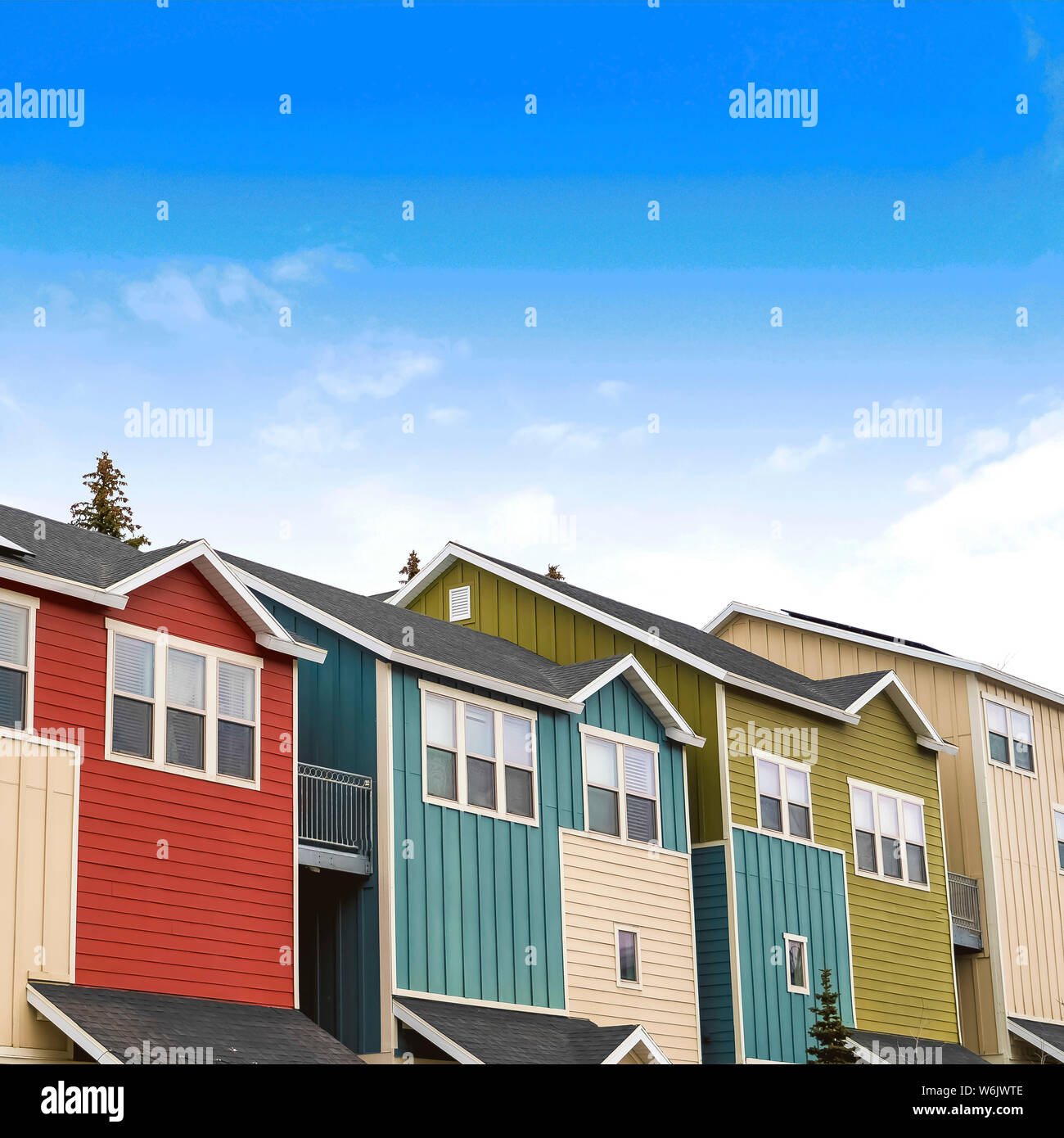 Square Houses with balconies and porches against blue sky and clouds on ...