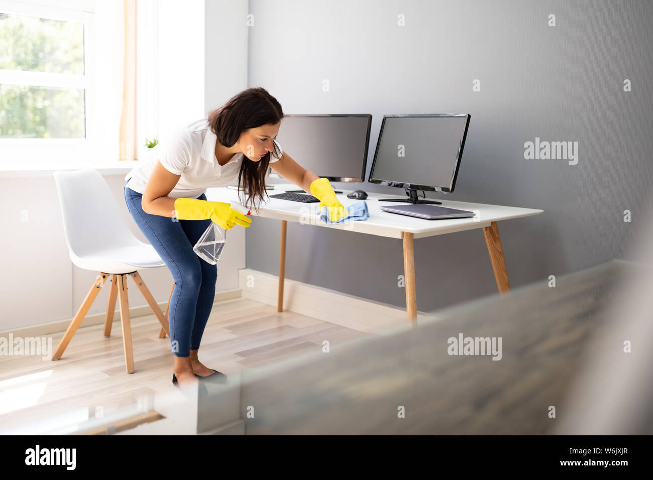 Side View Of Female Janitor Cleaning Desk With Blue Napkin In Office ...