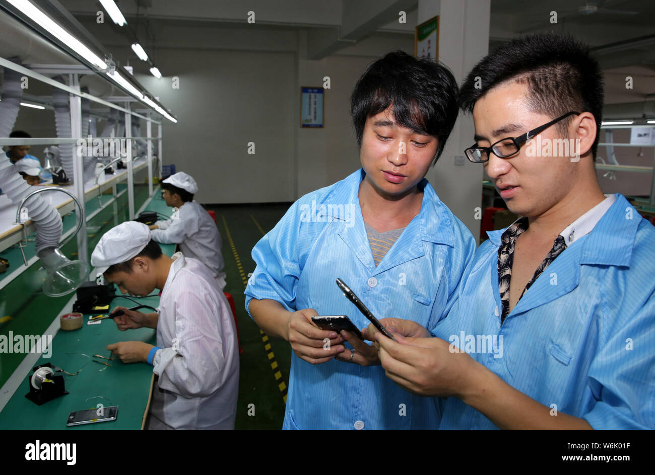 --FILE--Chinese workers check mobile phones at a factory in Huaying ...
