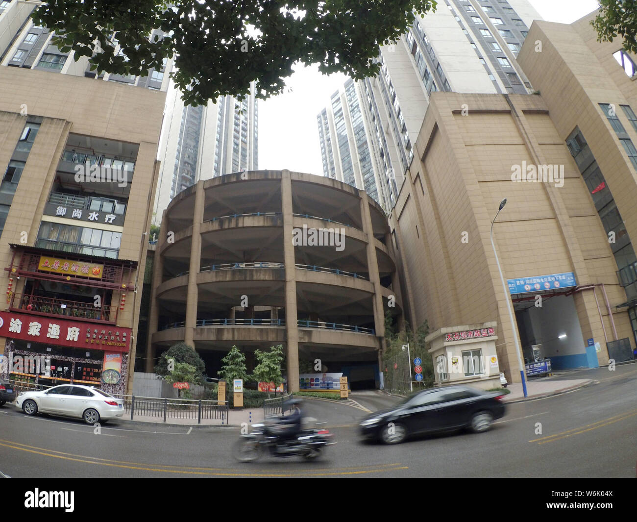 Cars drive past the 5-story high spiral parking lot at a residential ...