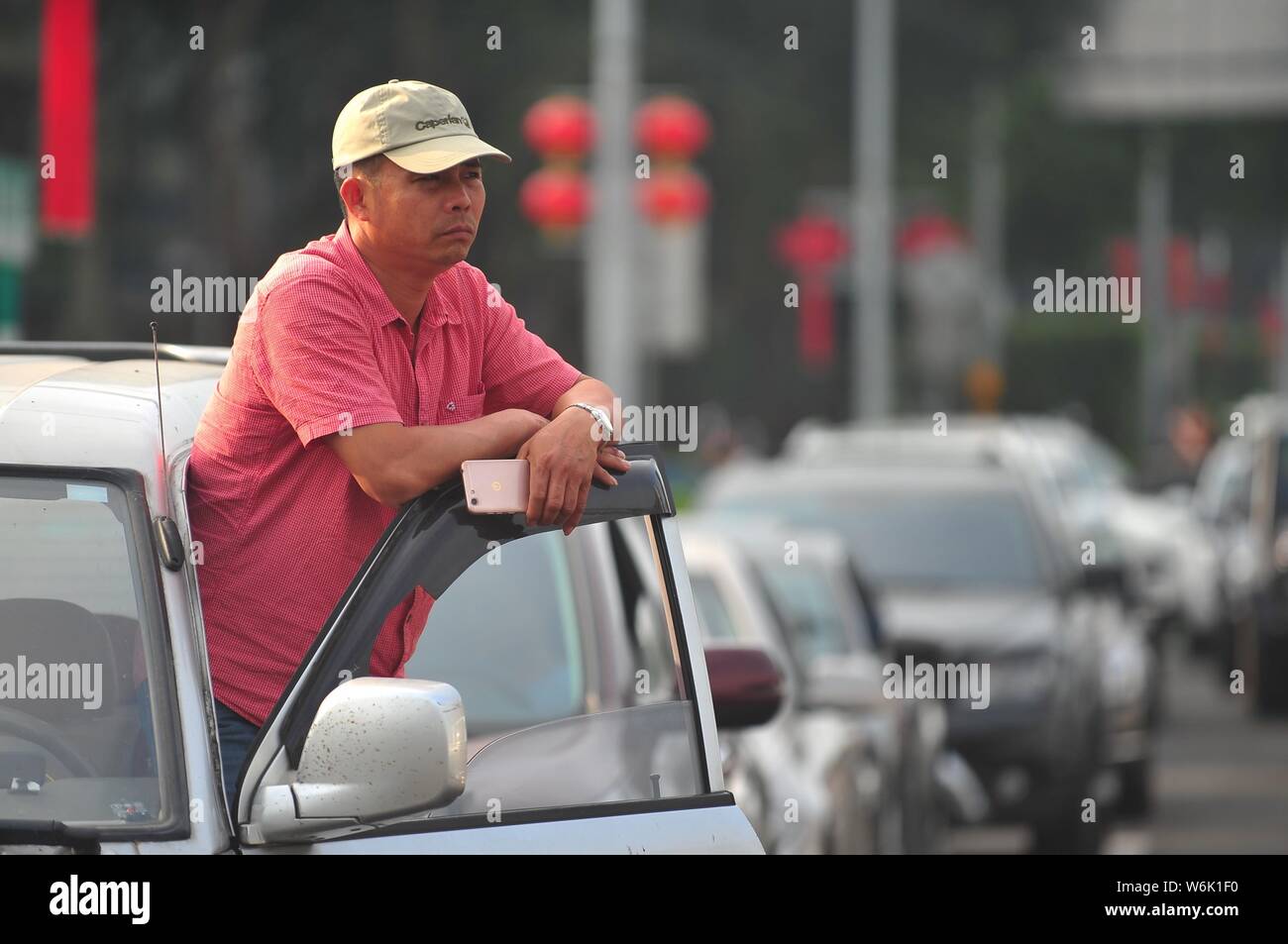 A car owner gets off his car to take a rest as masses of vehicles line ...