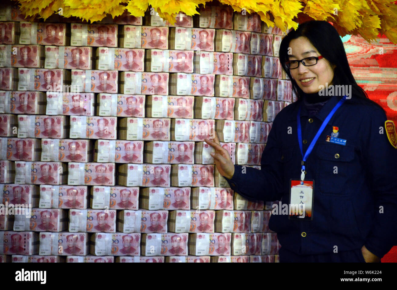 A Chinese employee poses with bundles of 100-yuan RMB (Renminbi ...