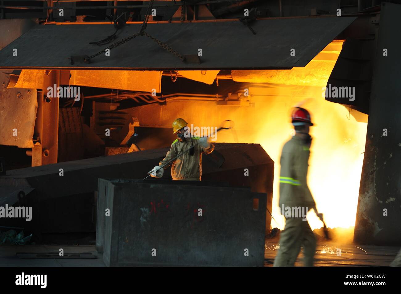 --FILE--Chinese workers survey the production of steel next to a ...