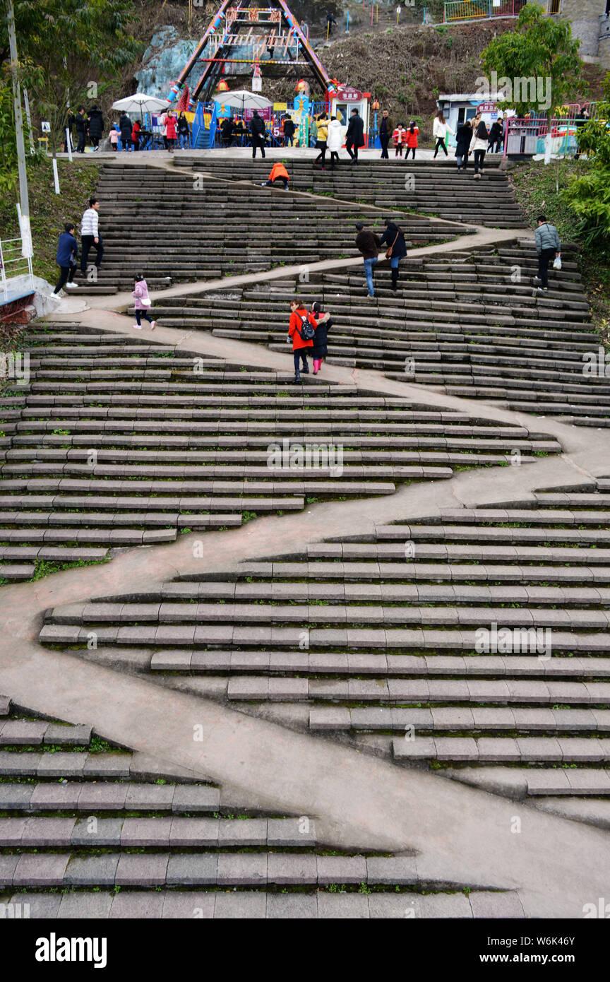 Tourists and local residents climb stairs of a mountain and walk on the ...
