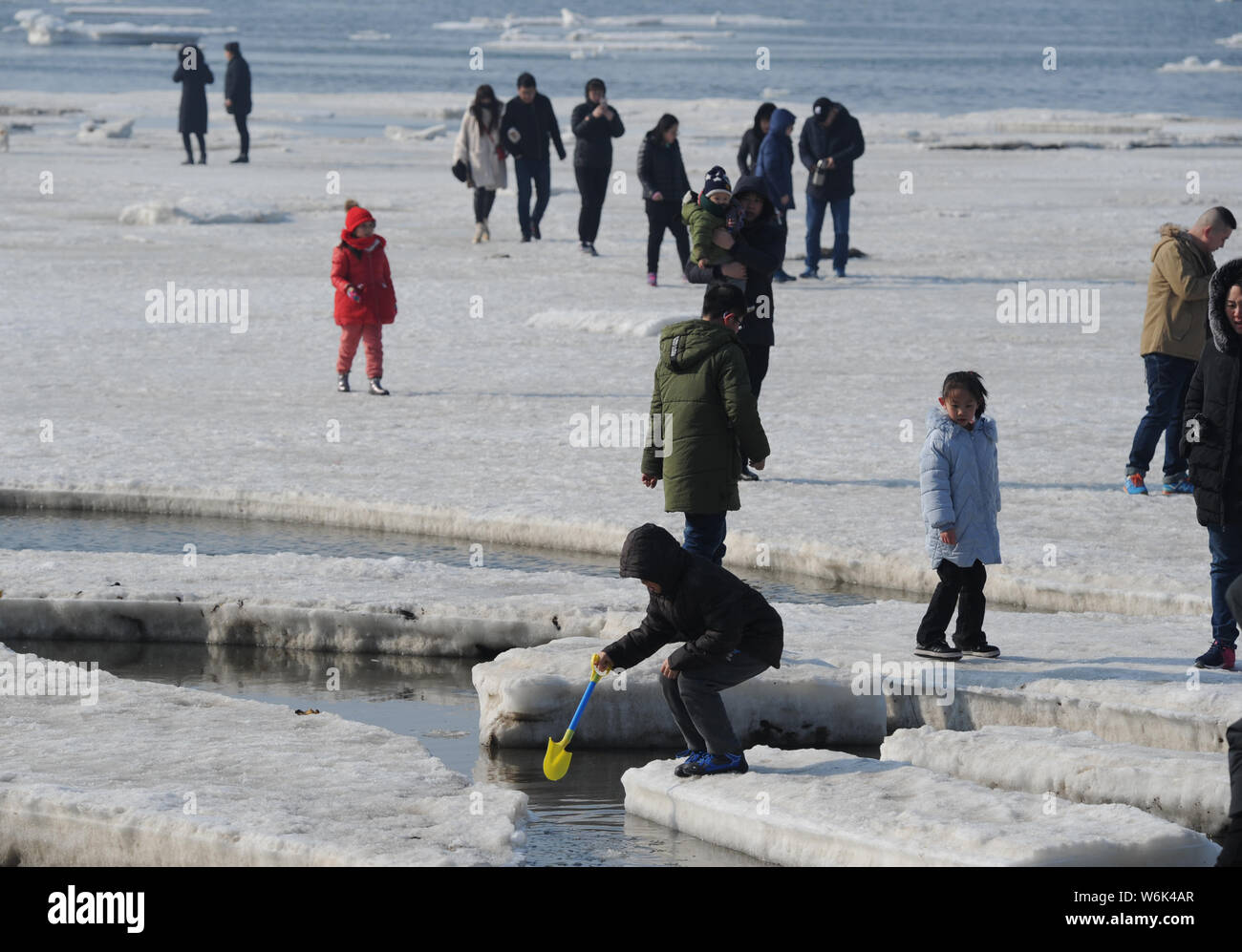 Tourists enjoy themselves on the floating melted sea ice at the Bohai ...