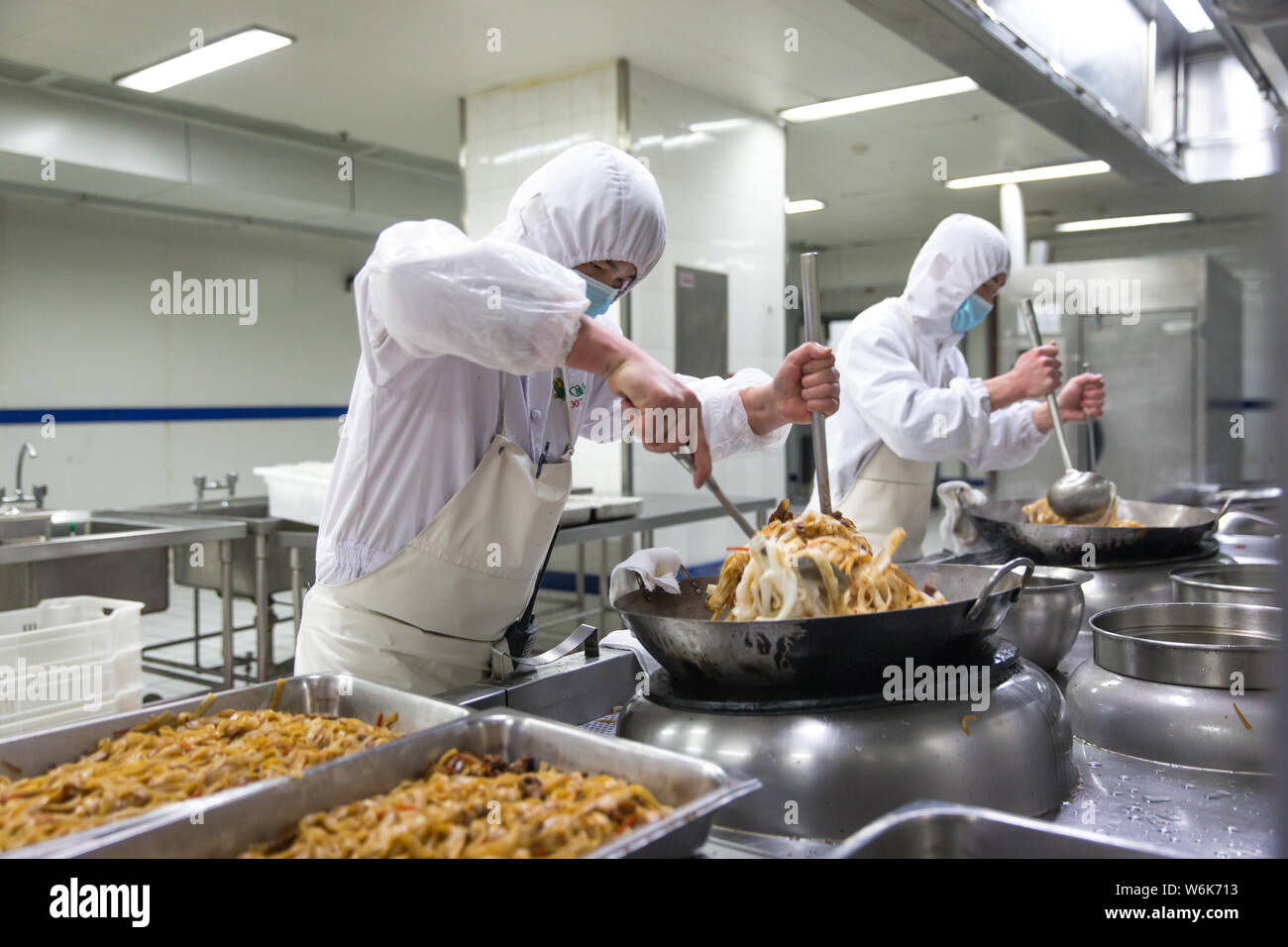Chinese workers stir-fry rice noodles with beef at a food processing ...