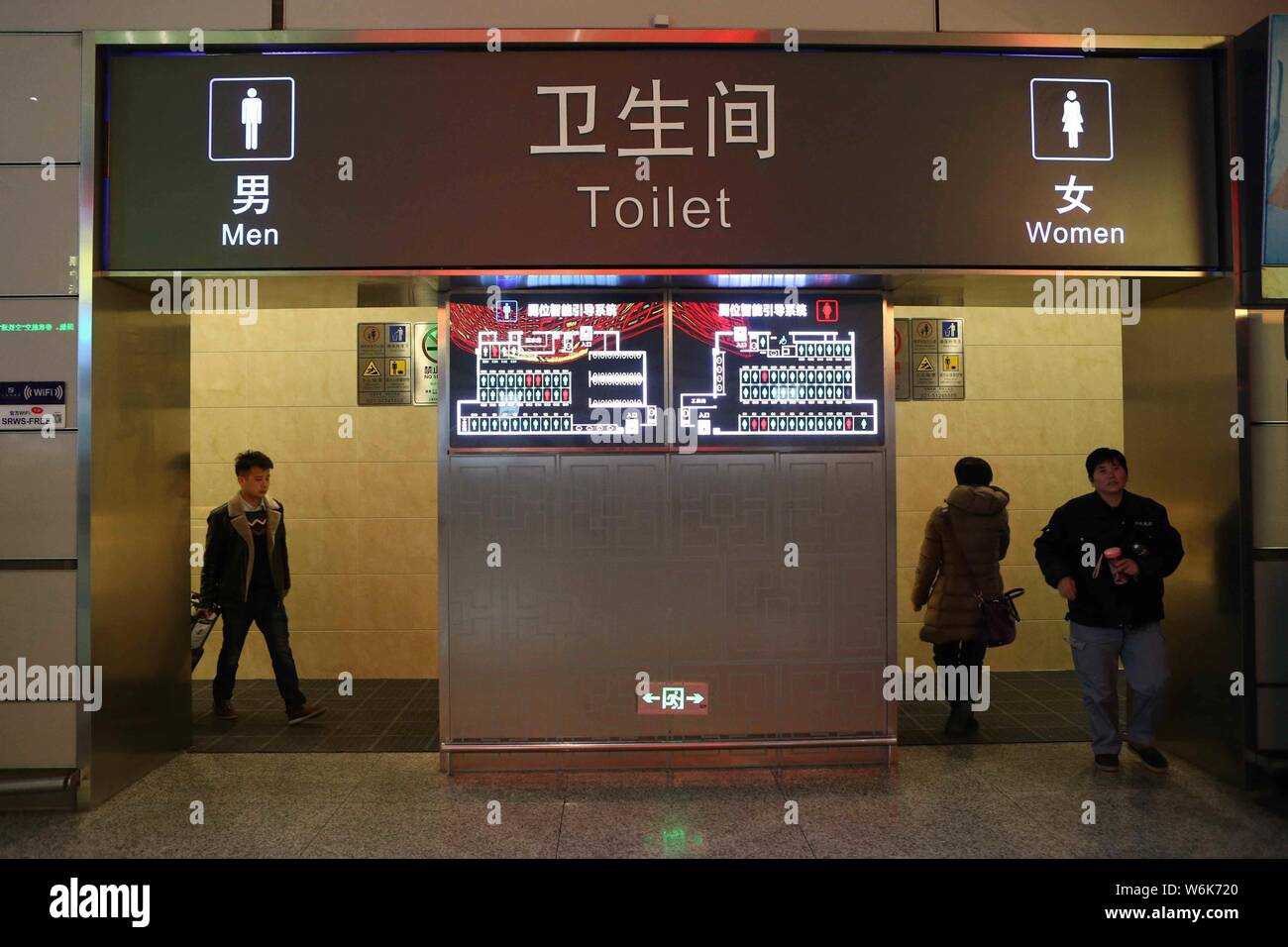 Passengers walk into a toilet with an electronic display showing the ...